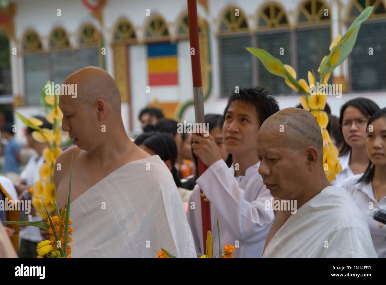 Novice monks, one with tattoos on head, in ceremony walking around ...