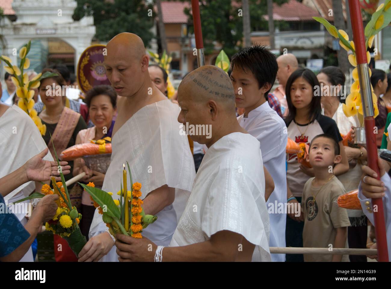 Novice monks, one with tattoos on head, in ceremony walking around ...