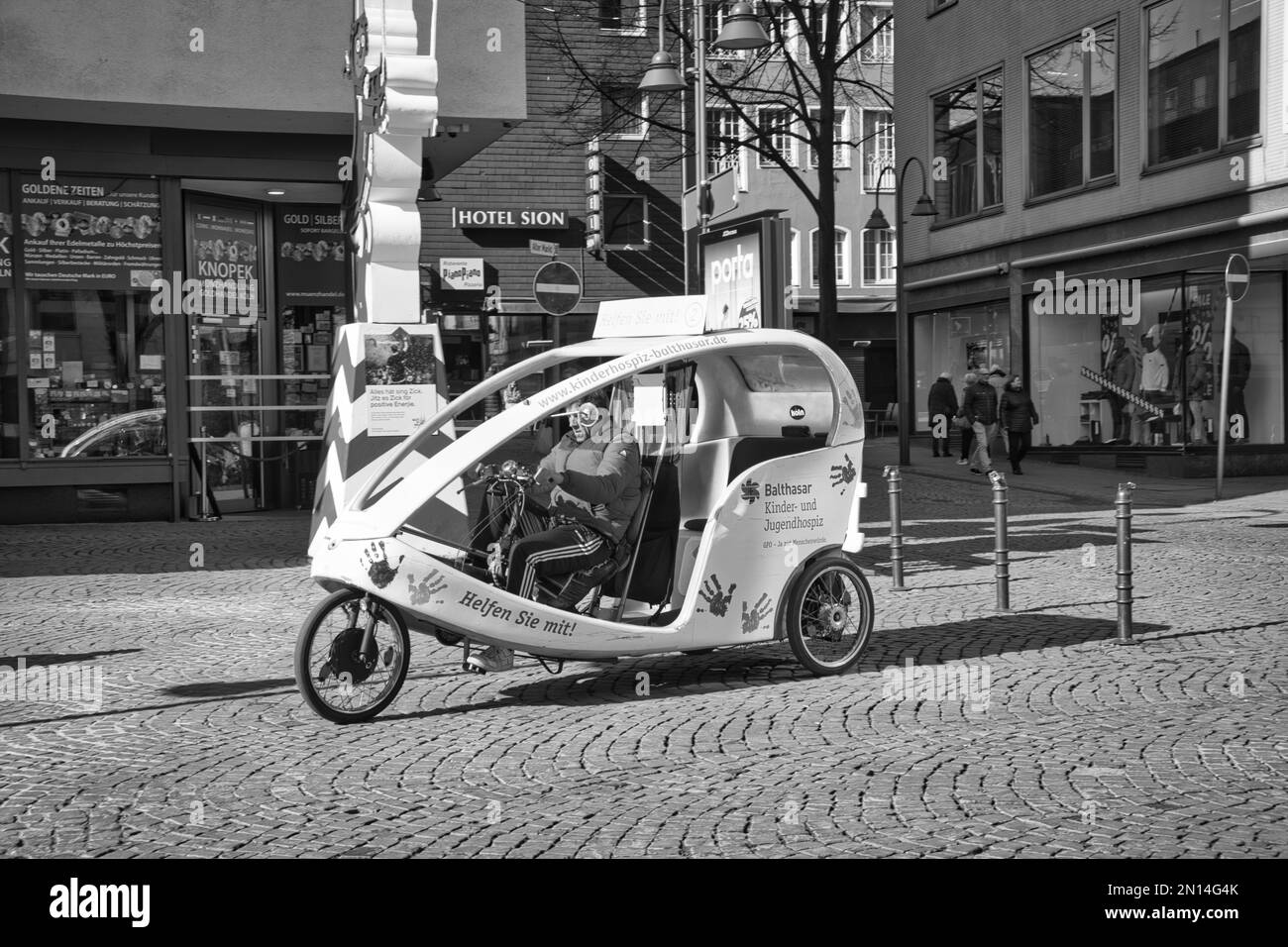 A grayscale shot of buildings and a rickshaw along a street in Cologne ...