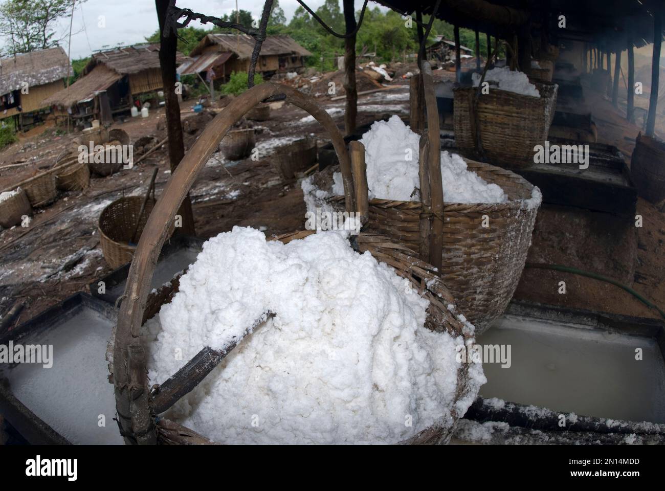 Salt in baskets over trays of boiling saline water, shacks in ...