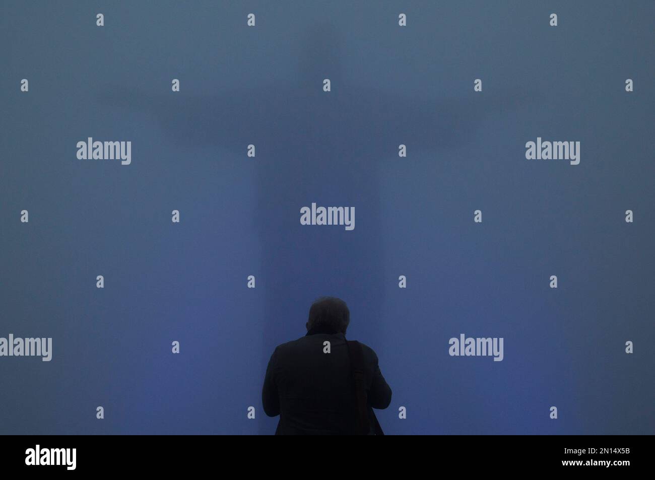 A man stands in front of the Christ the Redeemer statue, obscured by ...