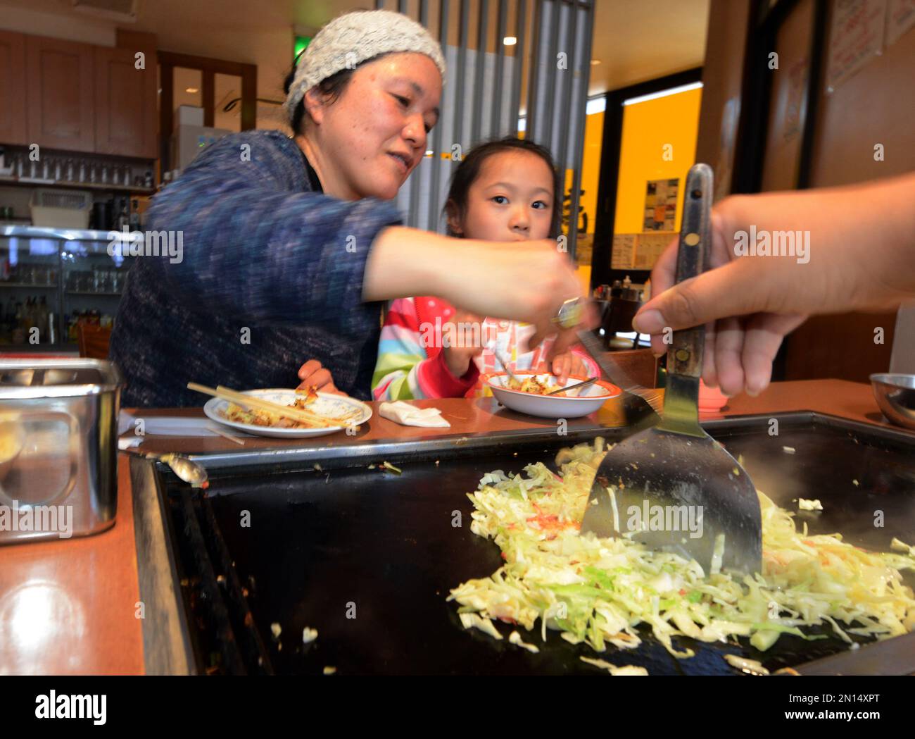 A Japanese woman cooking Okonomiyaki on a teppan in Tokyo, Japan Stock ...