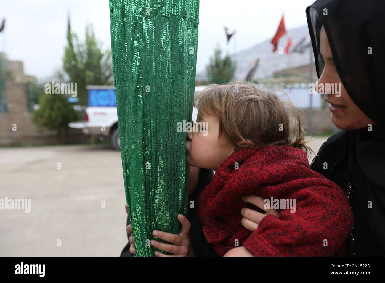 An Afghan girl kisses a mace for blessings during the holy day of ...
