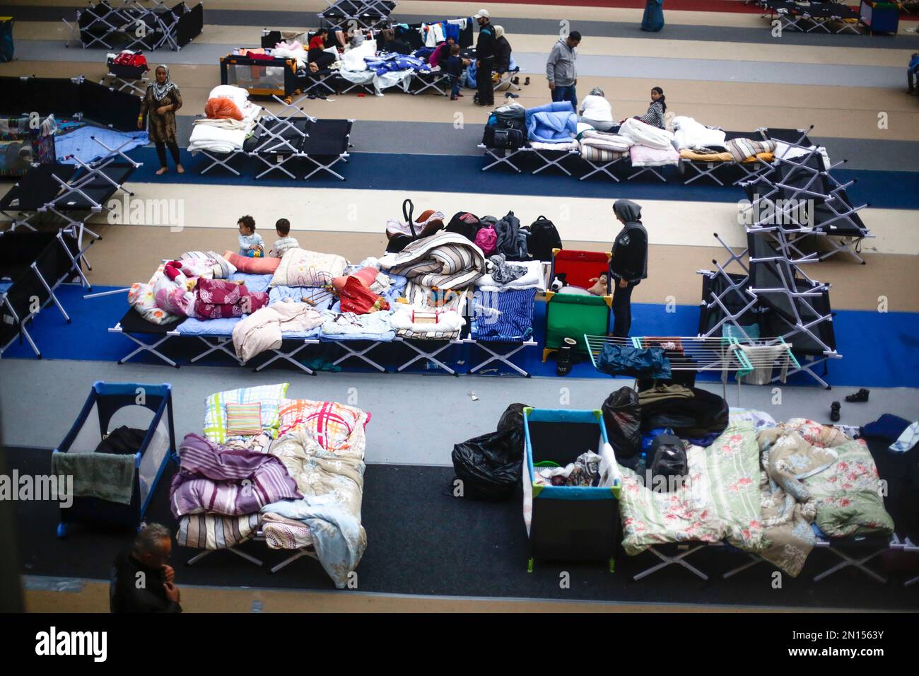 Migrants sit on camp beds at an emergency refugee shelter at a sports ...