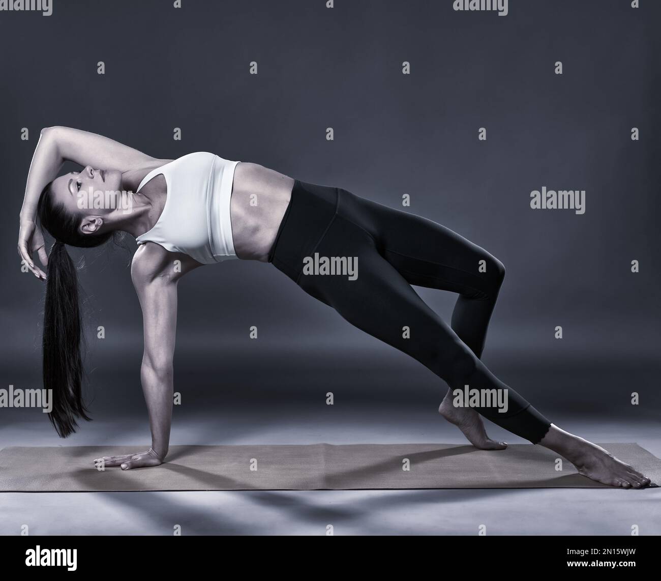 Monochrome toned of a woman yoga trainer doing Camatkarasana (Wild ...