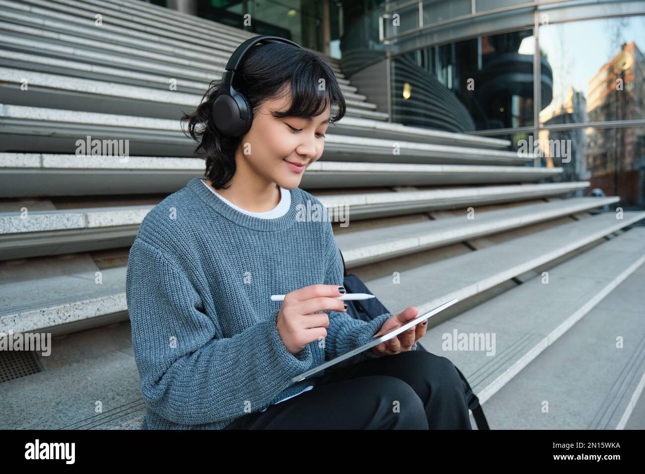 Young smiling digital artists works on her project using tablet and ...