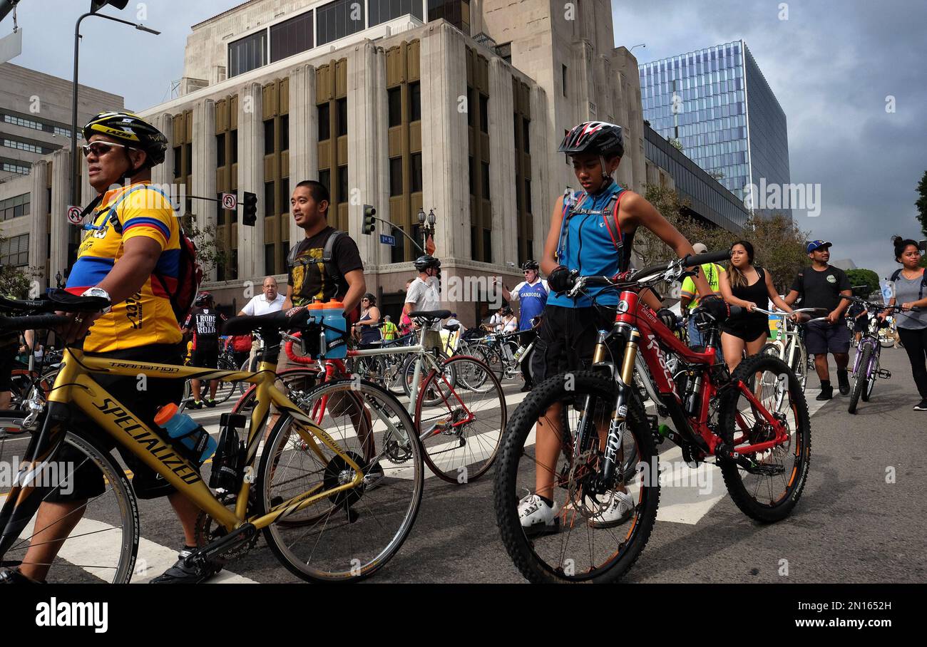 Cyclists walk their bikes through an intersection of downtown Los ...