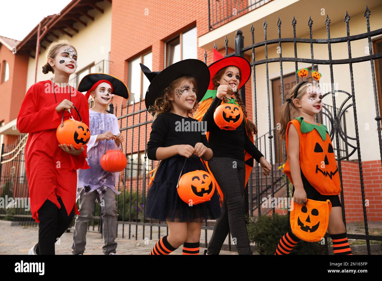 Cute little kids wearing Halloween costumes going trick-or-treating ...