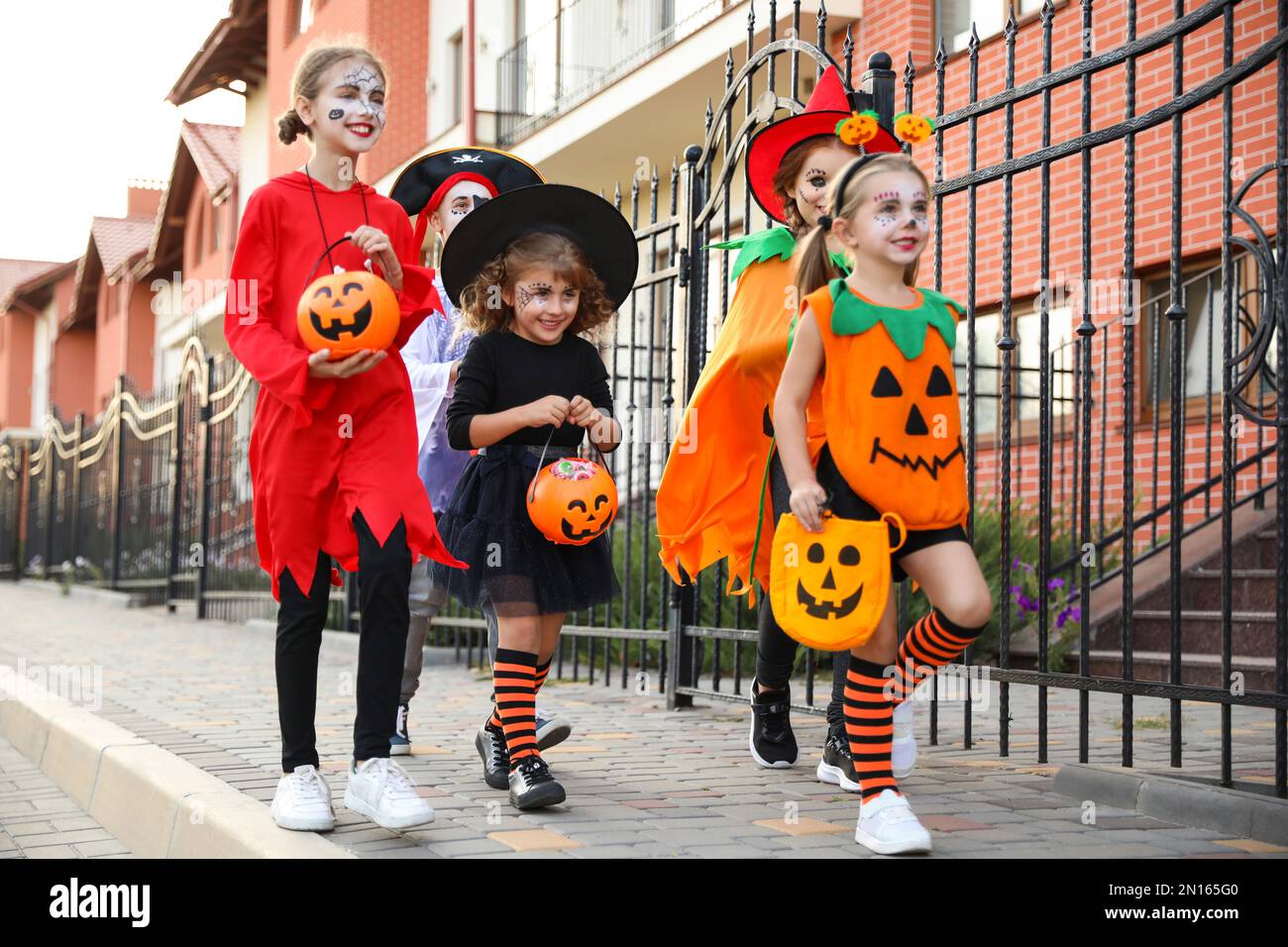 Cute little kids wearing Halloween costumes going trick-or-treating ...