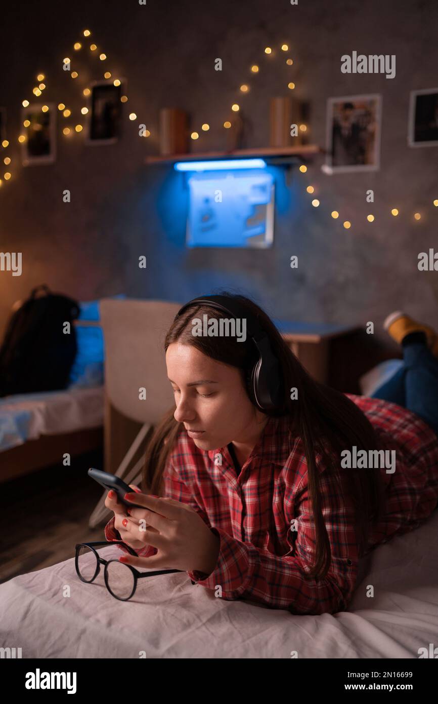 Female student wear headphones lying in comfortable bed listening new ...