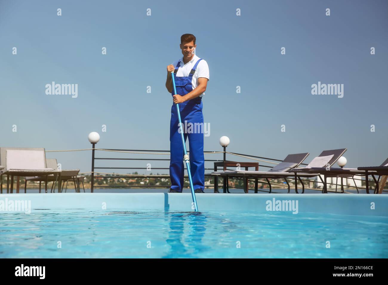 Worker cleaning outdoor swimming pool with underwater vacuum Stock ...