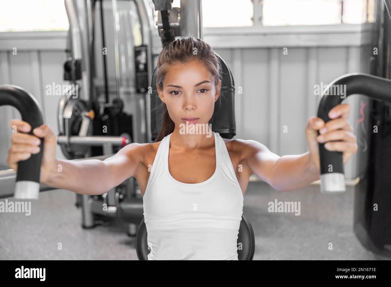 Gym workout Asian woman focused and motivated training on pec deck ...