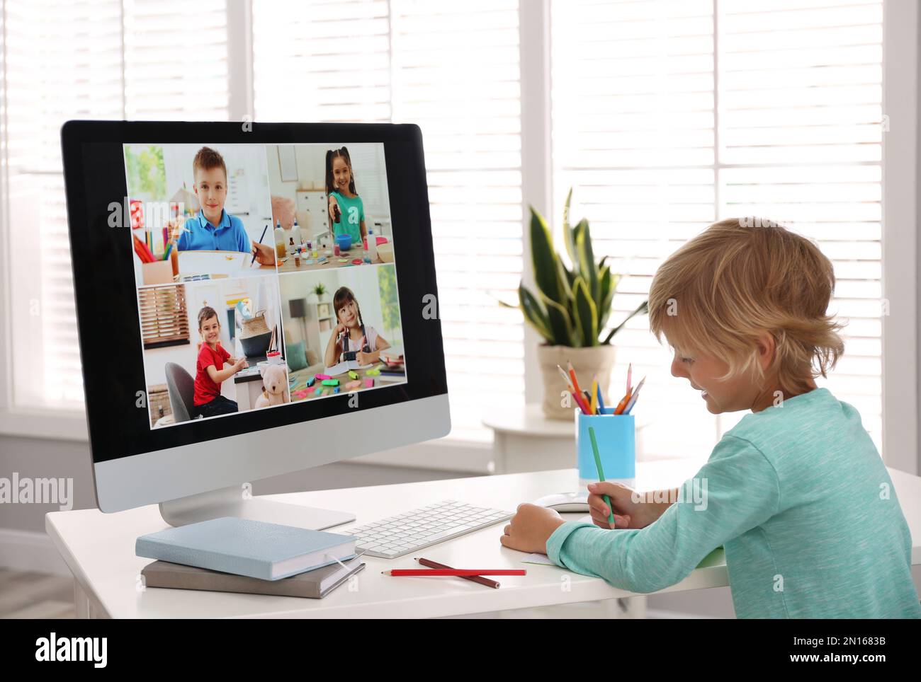 Little boy studying with classmates via video conference at home ...