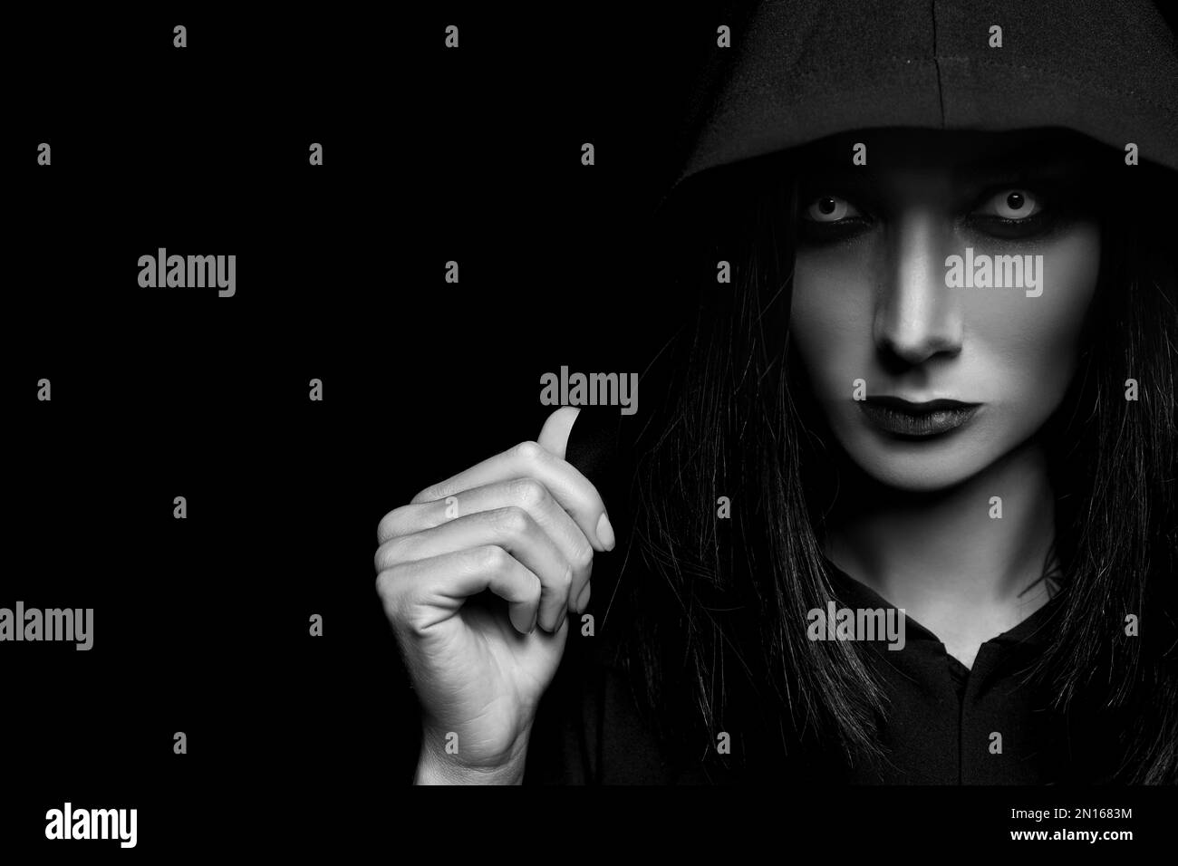 Mysterious witch with spooky eyes on dark background, space for text ...