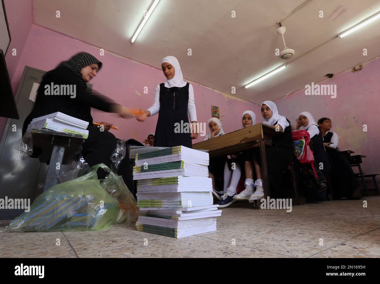 Iraqi students receive books and school supplies from their teacher on ...