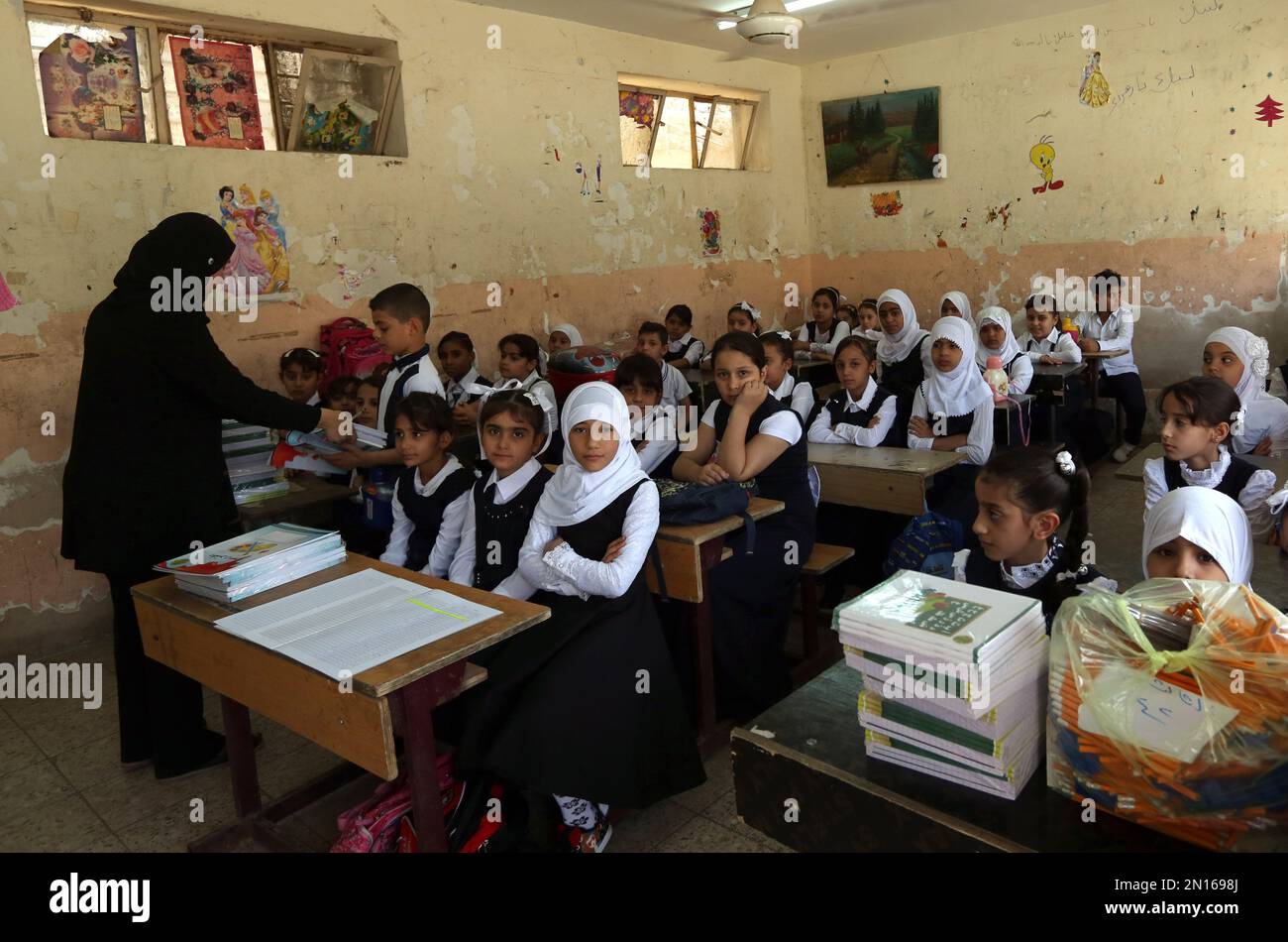 Iraqi students receive books and school supplies from their teacher on ...