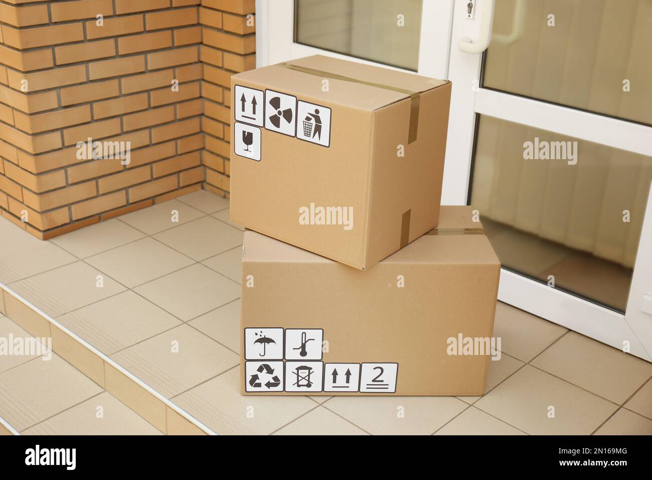 Cardboard boxes with different packaging symbols on floor near entrance ...