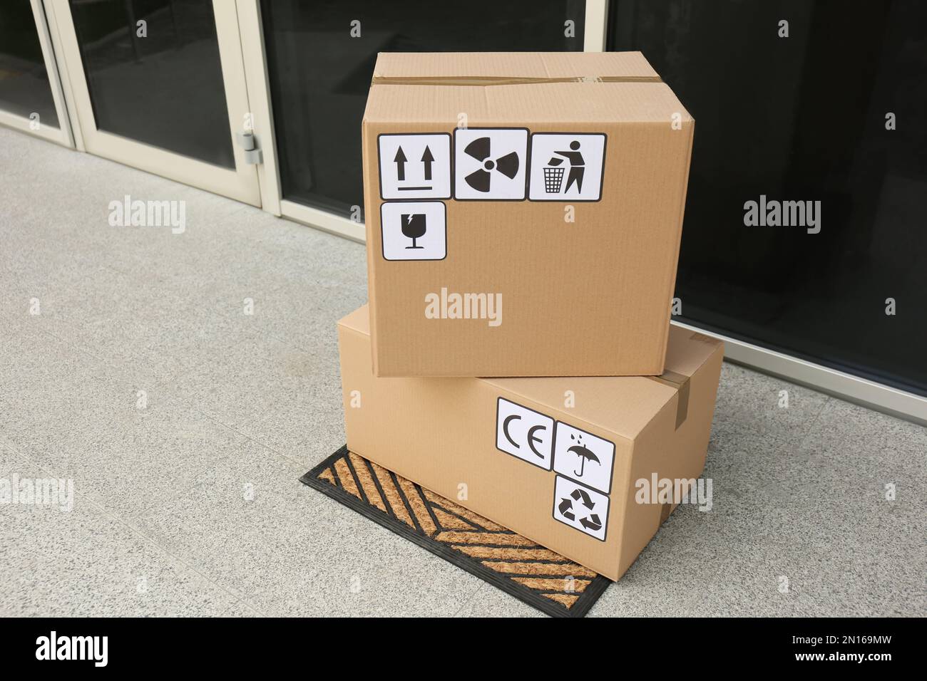 Cardboard boxes with different packaging symbols on door mat near ...
