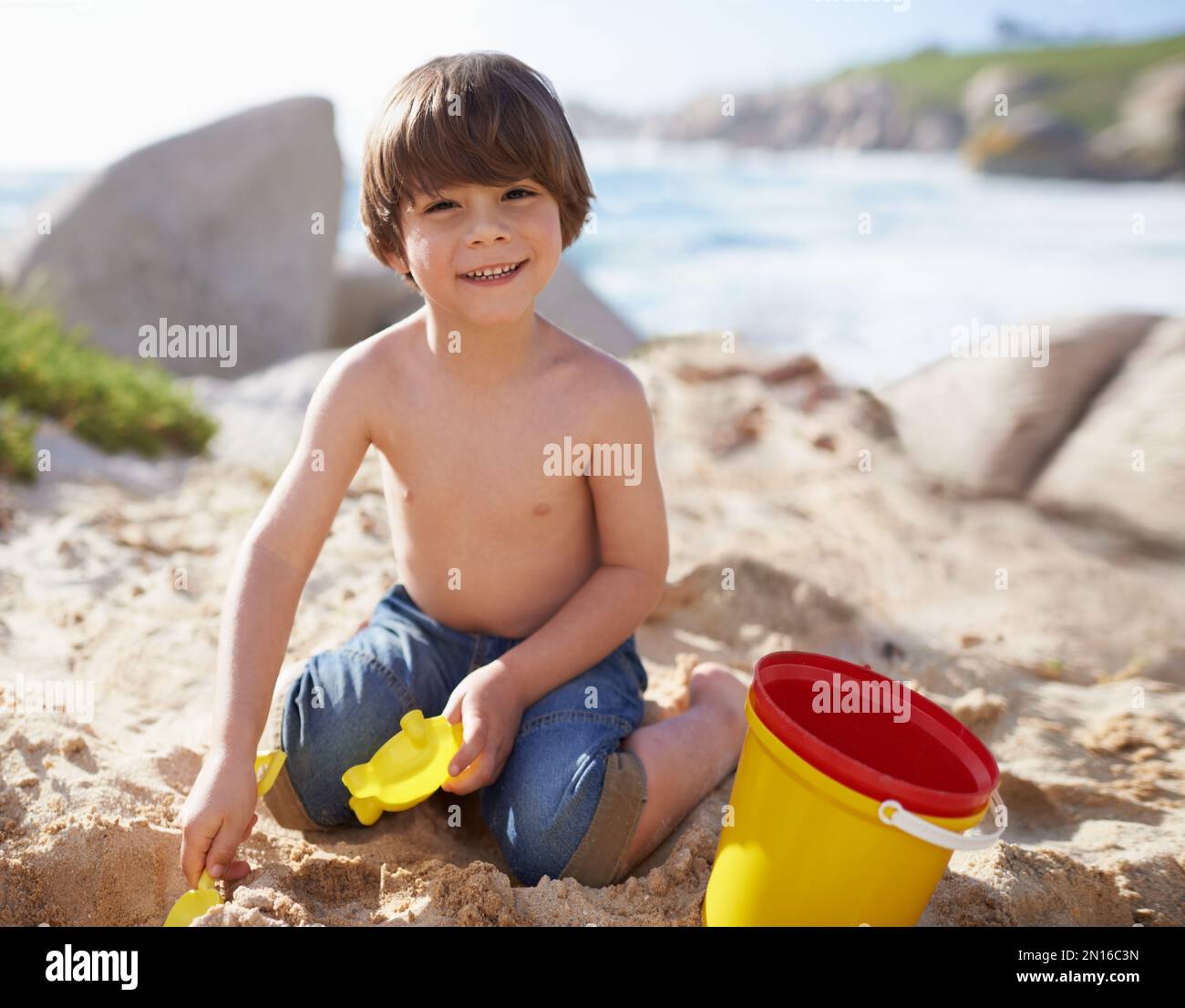 Building a sand fort. A young boy playing at the beach in the process ...