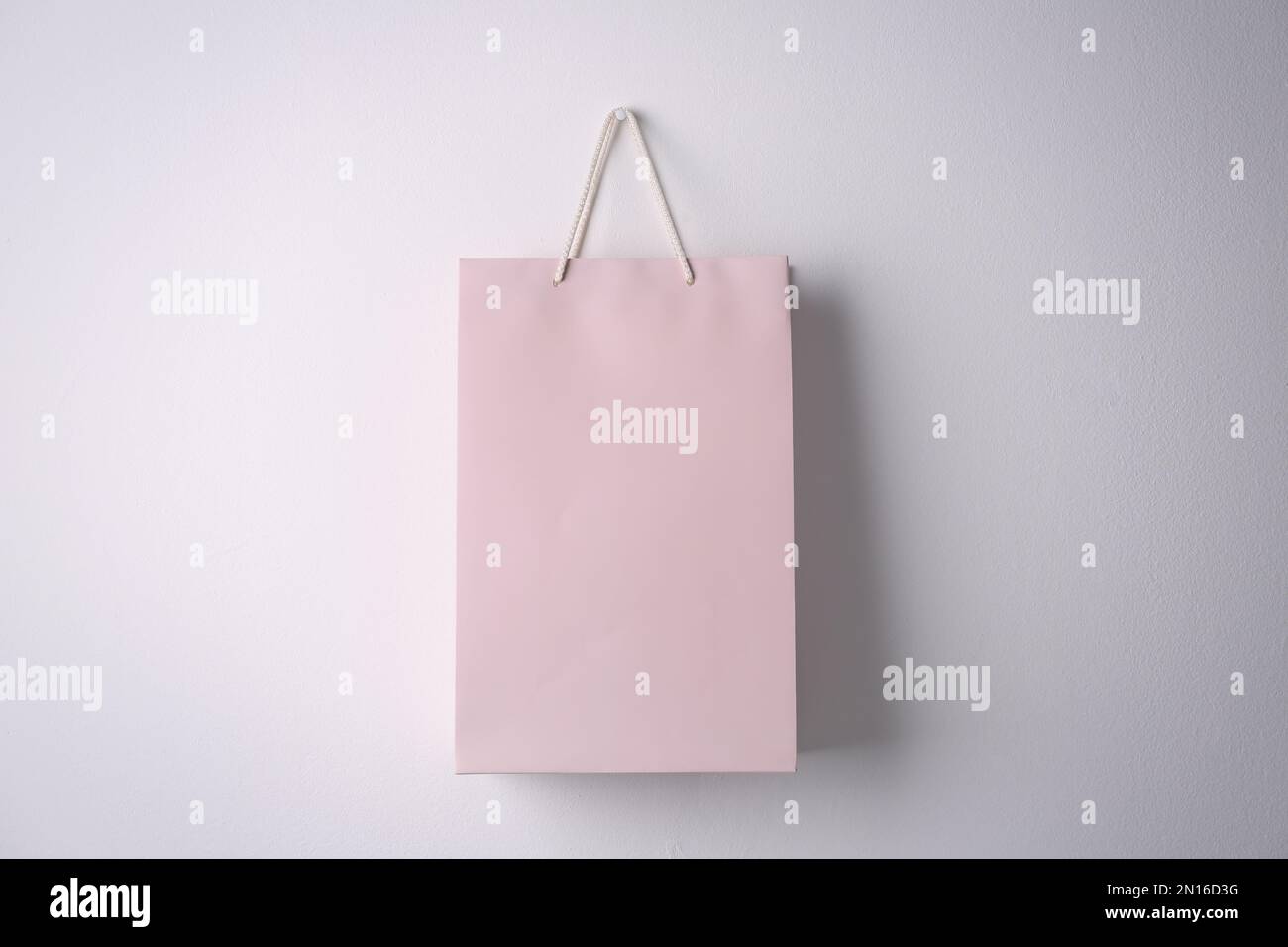 Paper shopping bag hanging on white wall Stock Photo - Alamy