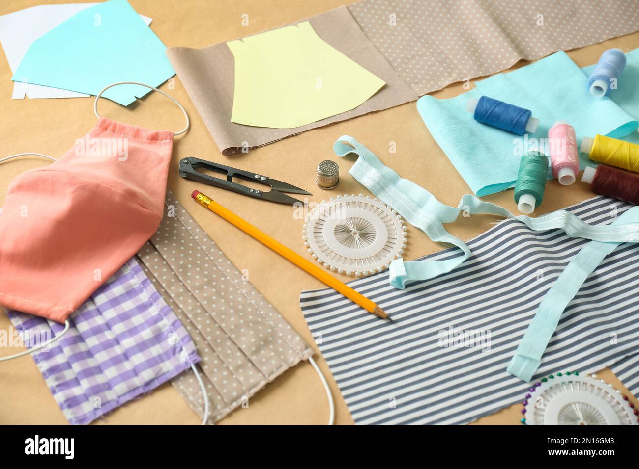 Fabric, sewing accessories and cloth masks on brown background ...