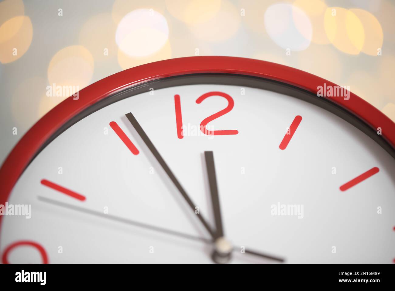 Clock showing five minutes until midnight on blurred background ...