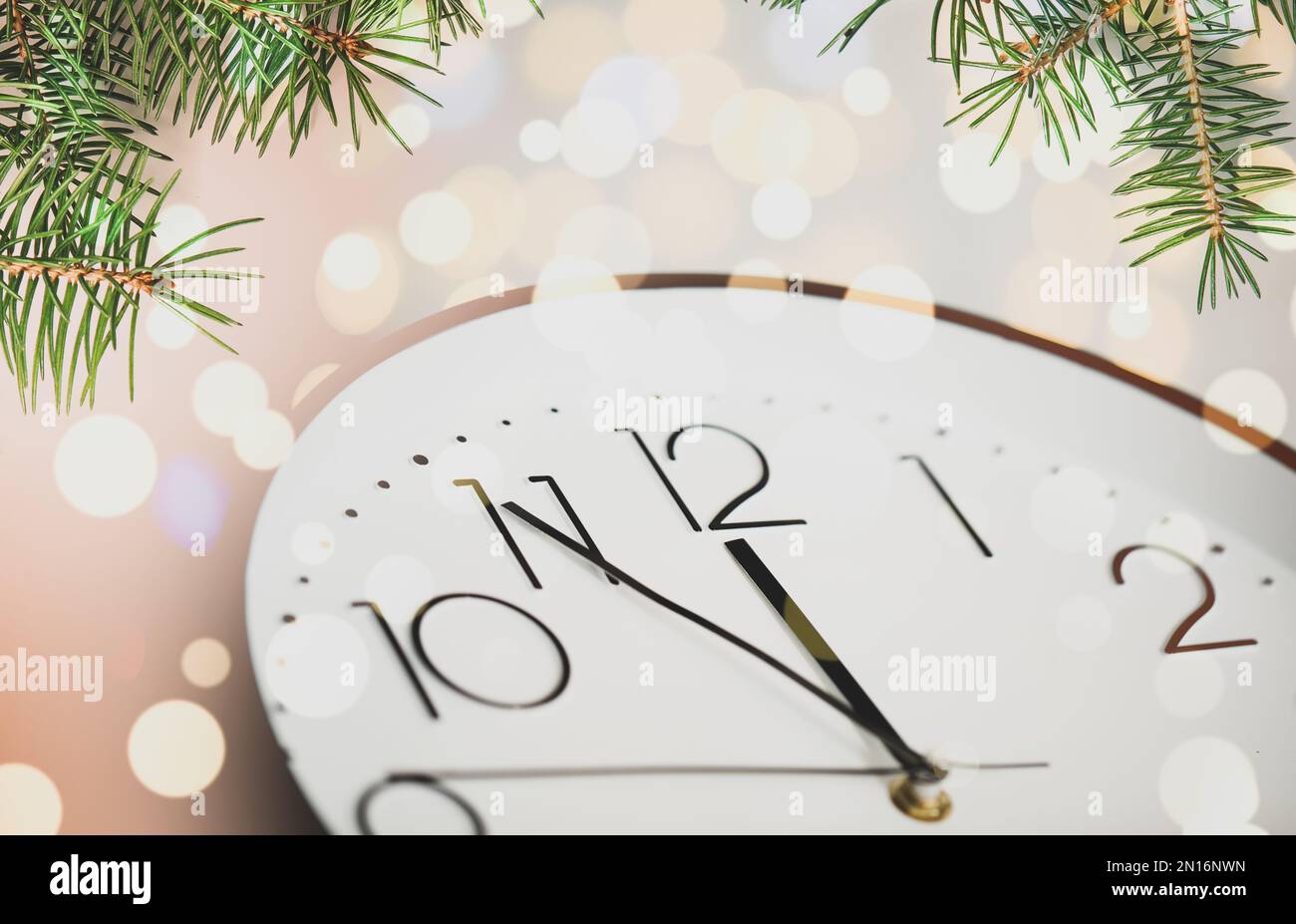 Clock showing five minutes till midnight with fir tree branches ...