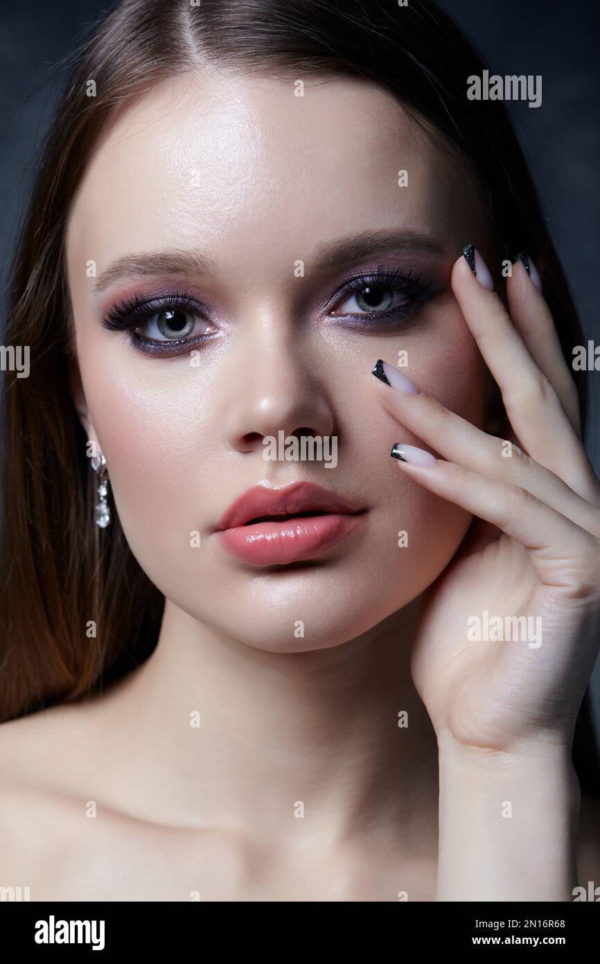 Portrait of female face. Hand with black french manicure nailsnear face ...