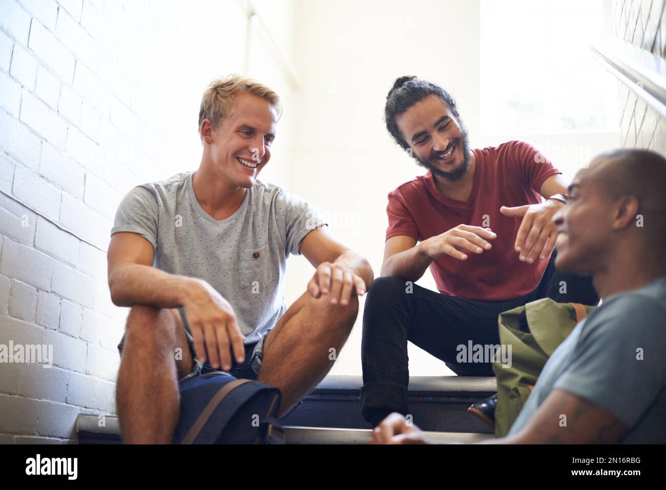 Living the university life. male university students sitting and ...