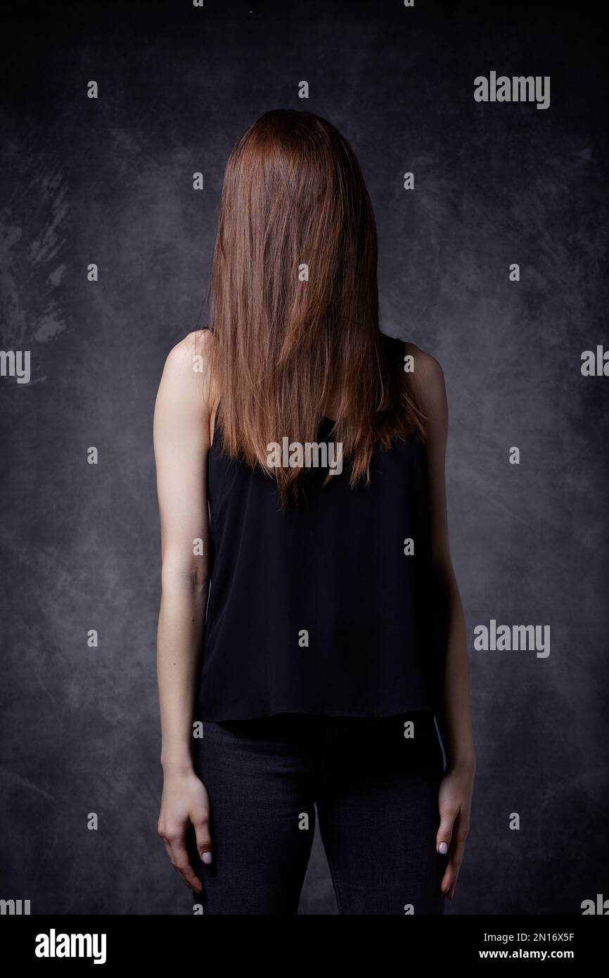 Young woman with long straight flowing hair. Hair covers the face. Gray ...