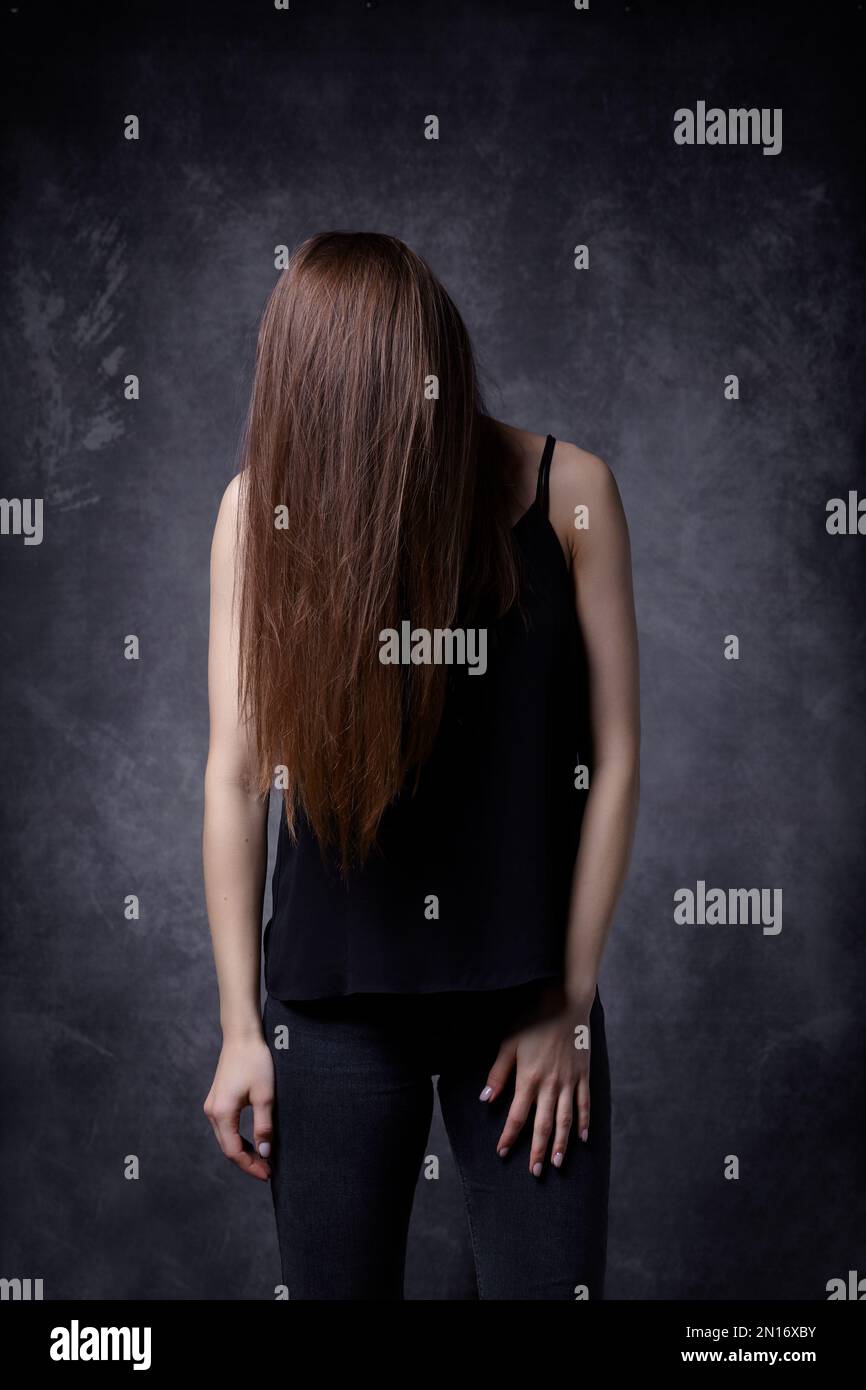 Young woman with long straight flowing hair. Hair covers the face. Gray ...