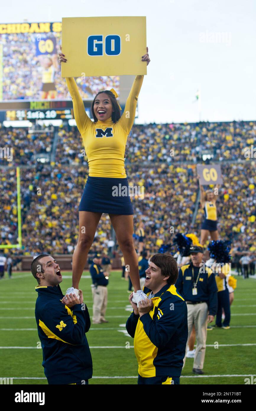 A Michigan cheerleader holds up a sign to cheer at the crowd from the ...