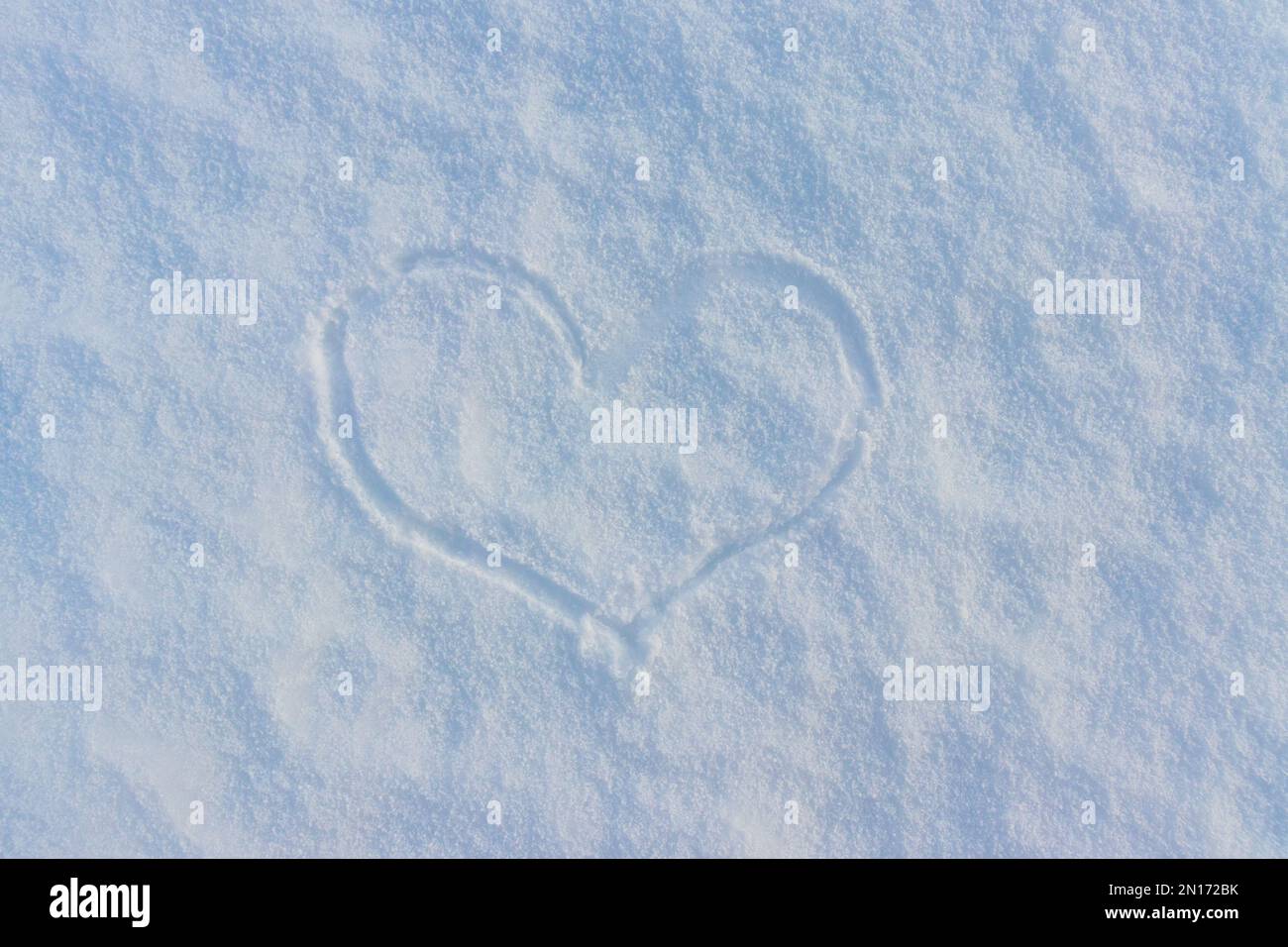 Top view, hand-drawn a heart shape on natural pure white soft snow ...