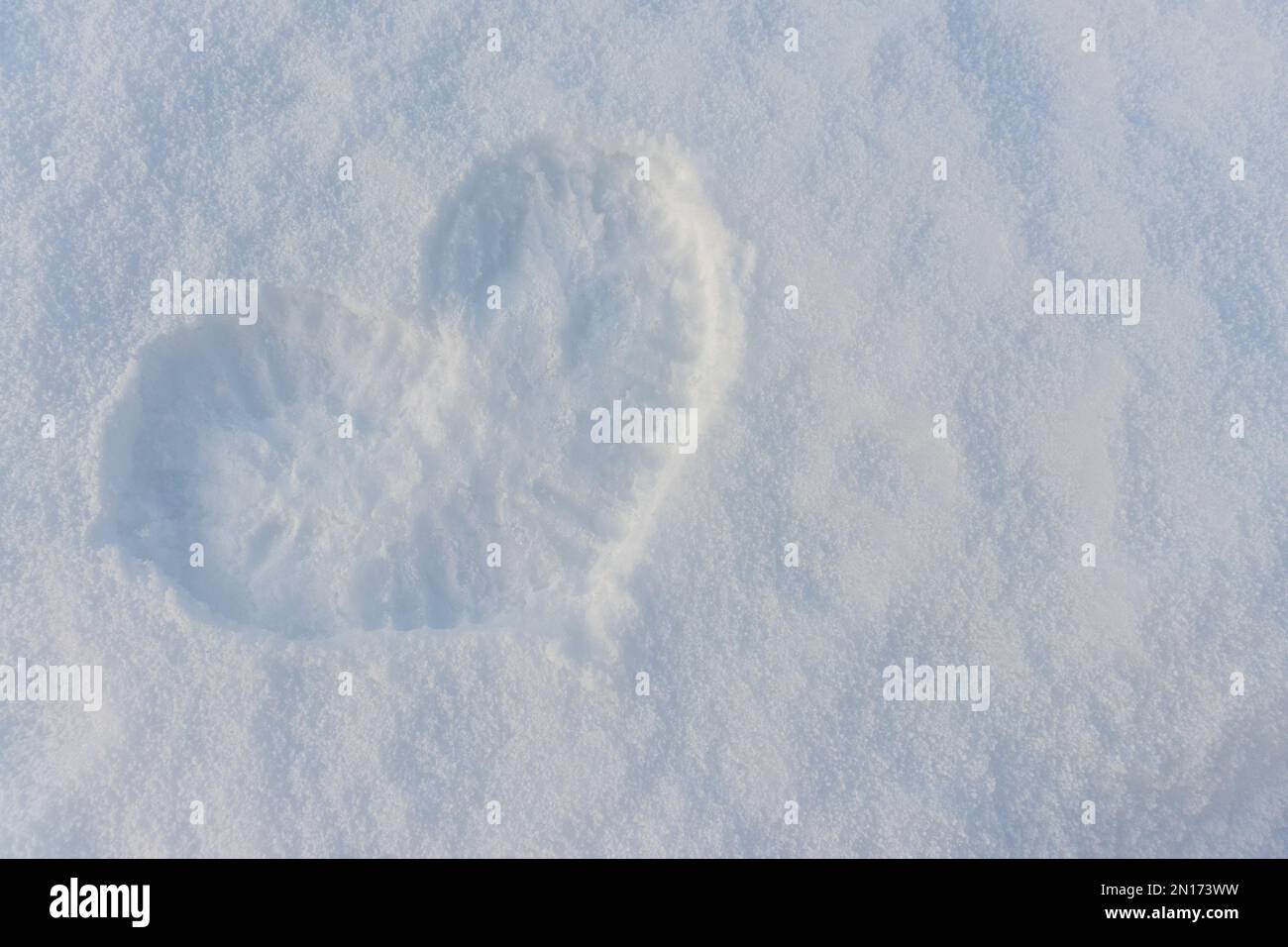 Top view, hand-drawn a heart shape on natural pure white soft snow ...