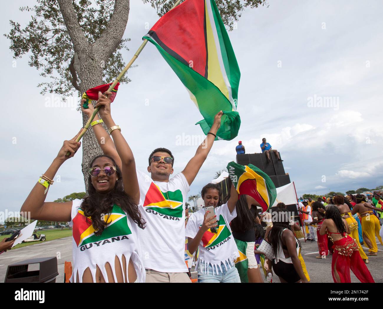 Attendees wave the national flag of Guyana as they watch dancers march ...