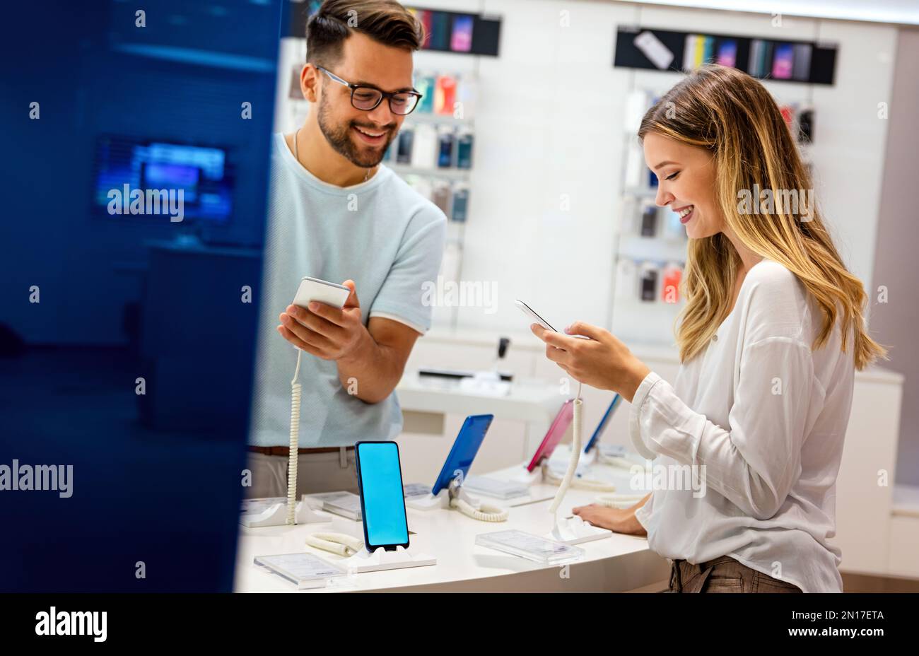 Happy young people shopping new mobile phone in a store. People ...
