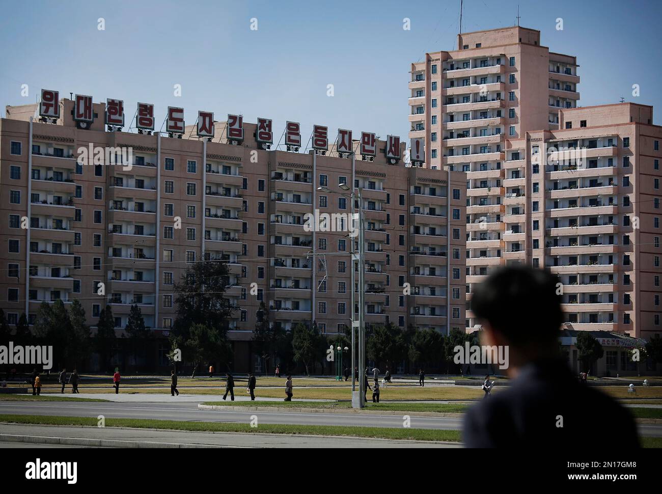 People walk past an apartment building decorated with a rooftop ...