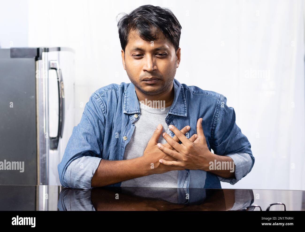 An Indian middle aged male feeling heart or chest pain sitting beside ...