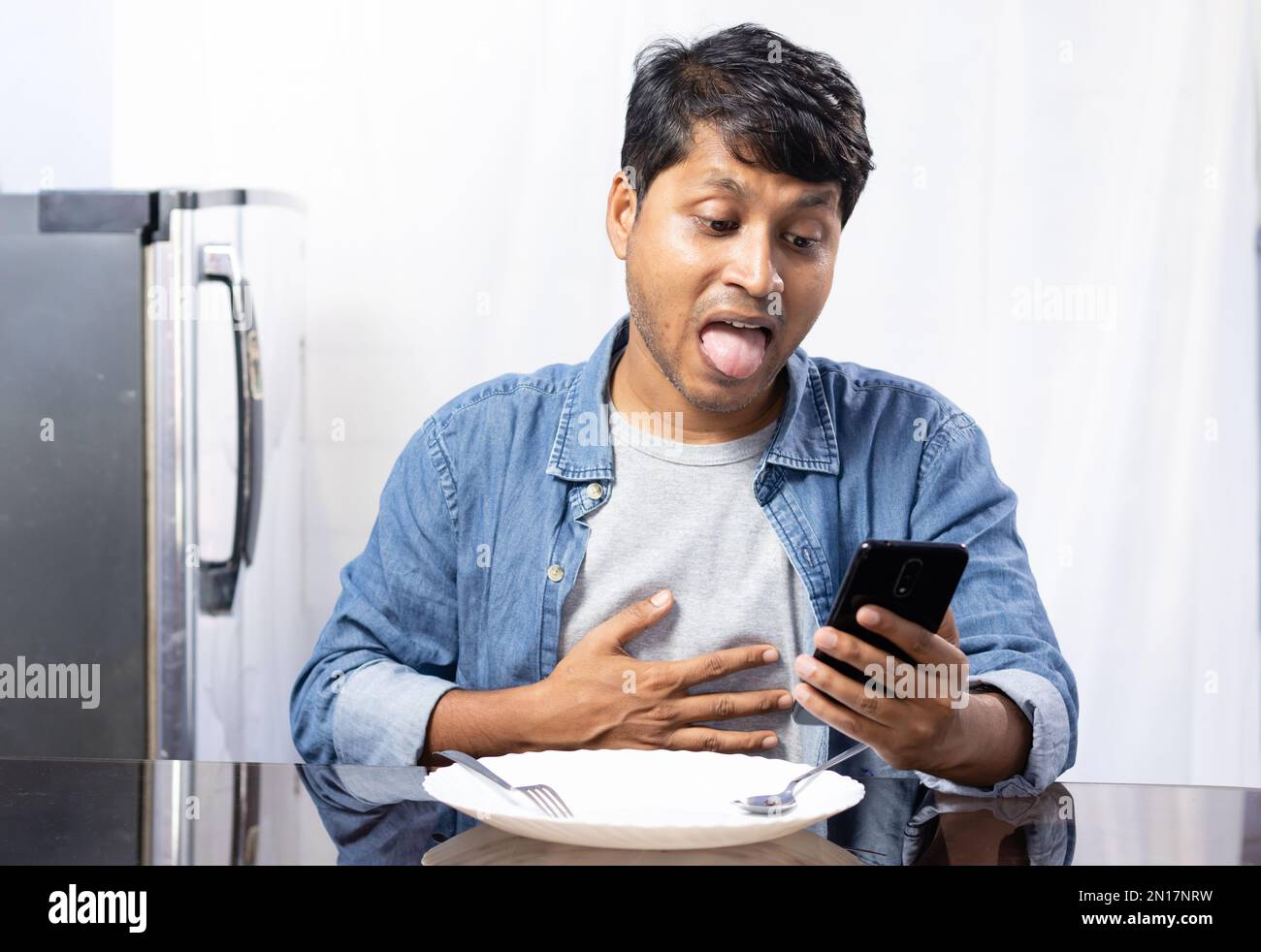 An Indian male ordering food with smart phone sitting beside dining ...