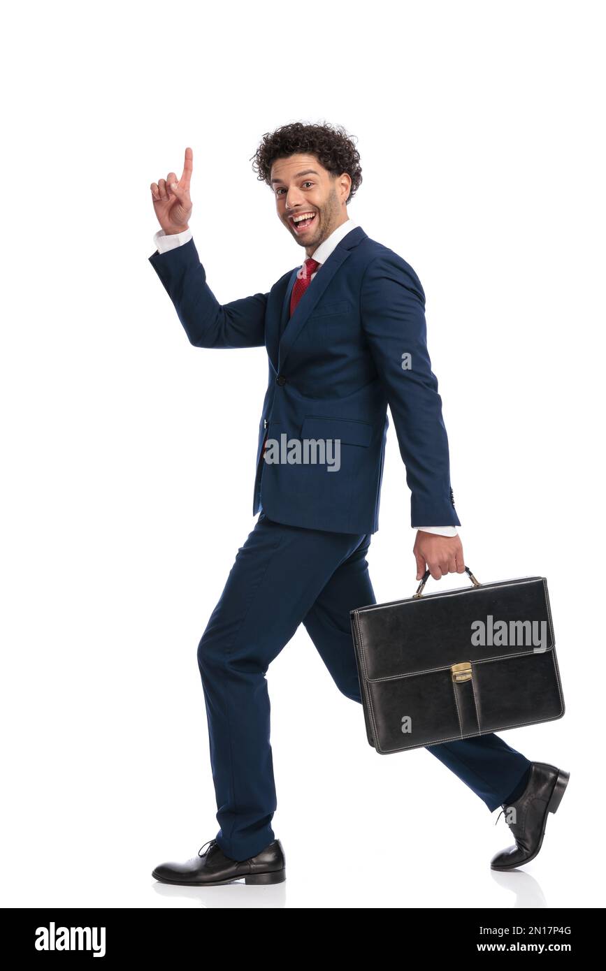side view of excited young businessman with bag pointing finger up ...