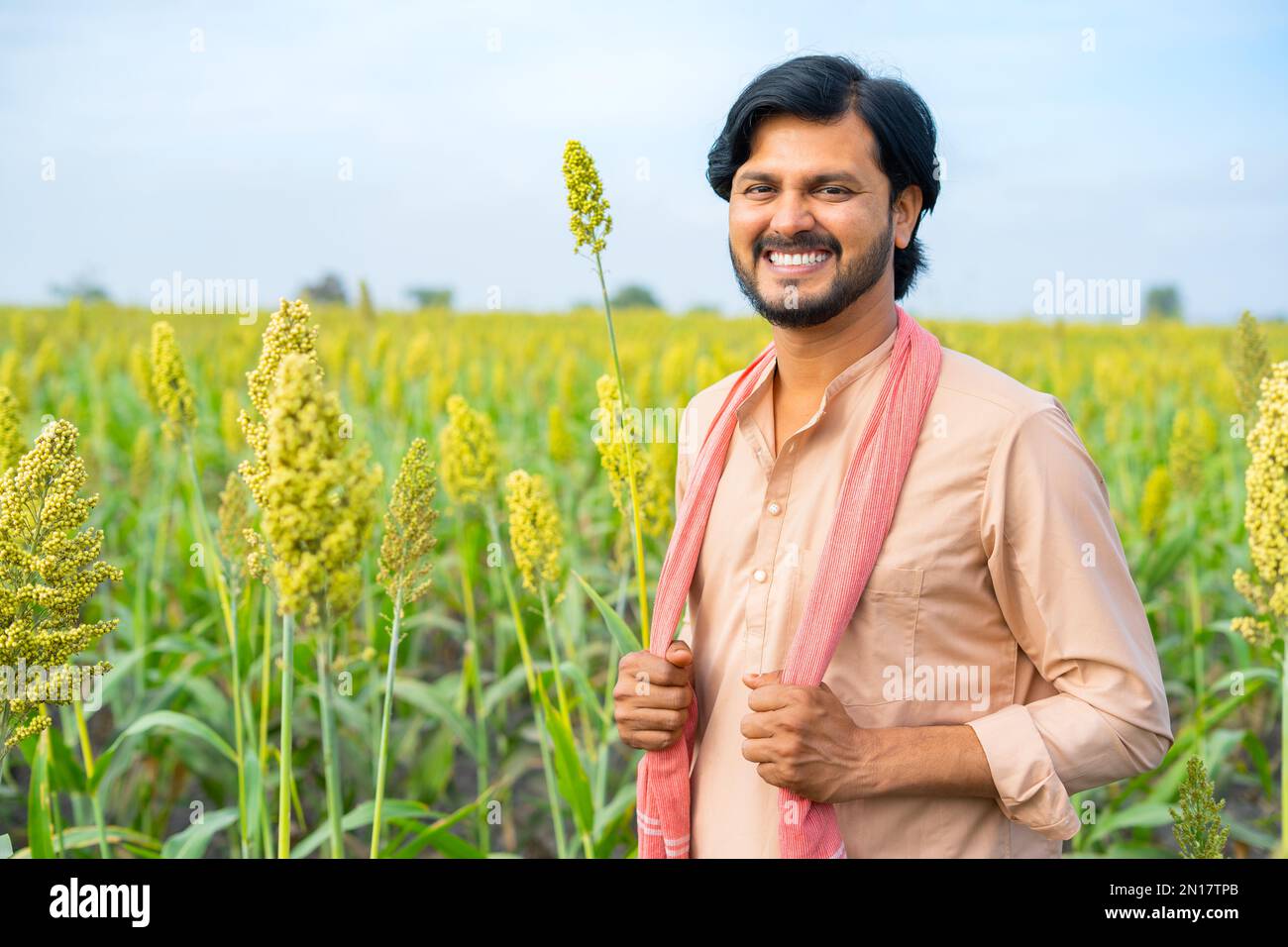 Portrait shot of happy young indian farmer standing with crossed arms ...