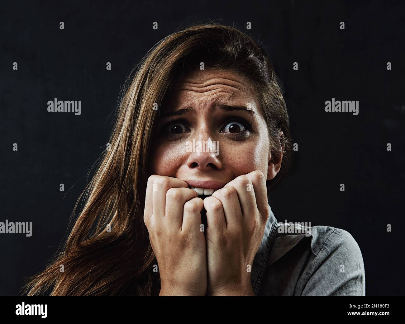 The face of terror. A terrified young brunette isolated on a black ...