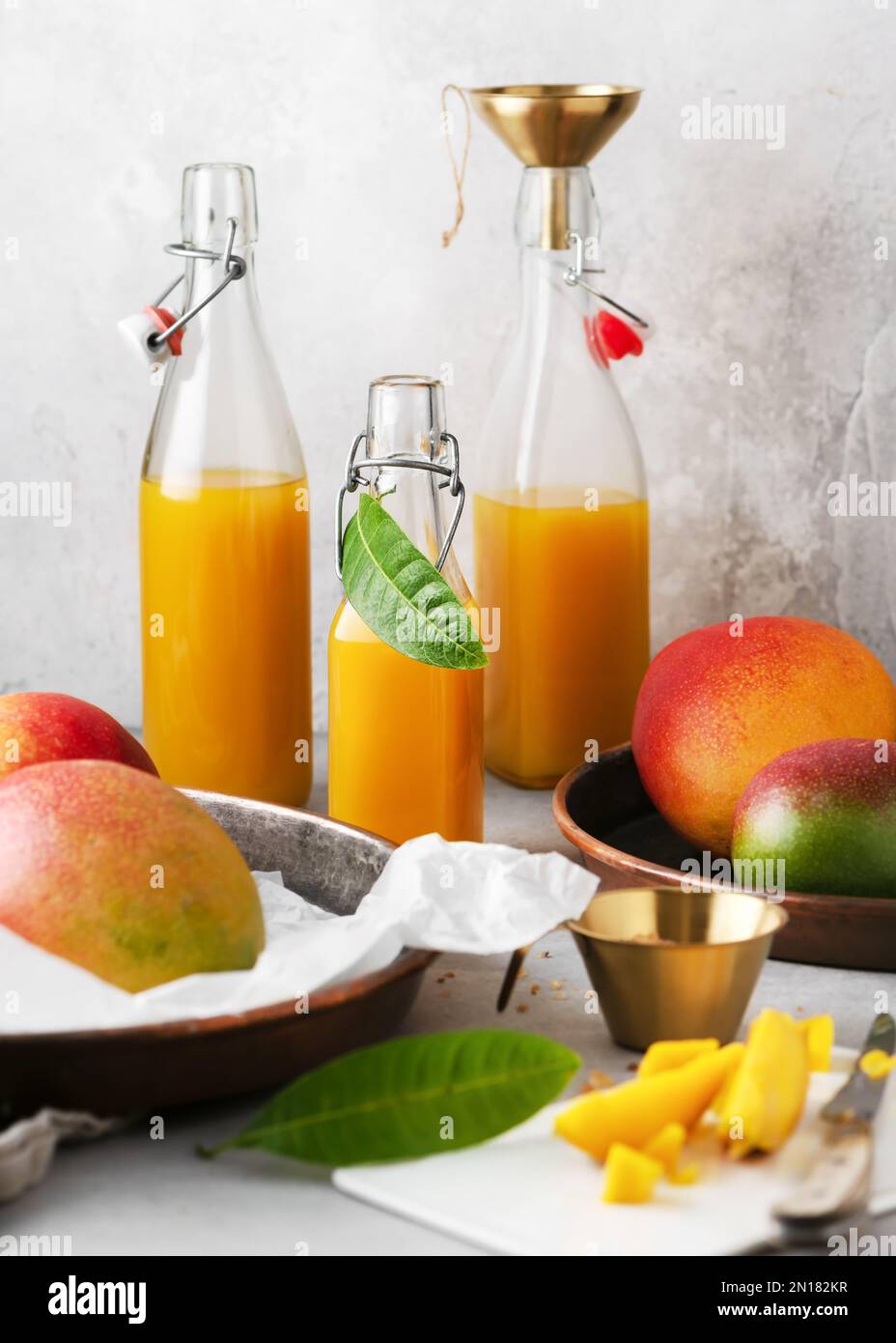 Delicious mango juice in glass bottles with fresh ripe fruit and leaves ...