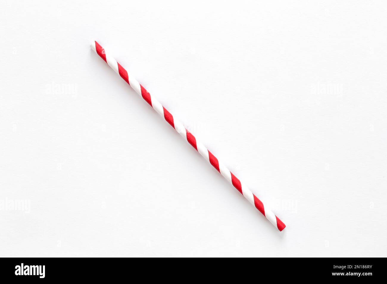 A single red drinking straw with red and white stripes on white ...