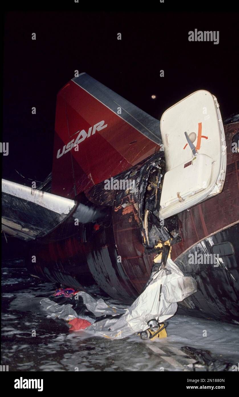 A deflated emergency evacuation slide hangs from an exit door of USAir ...