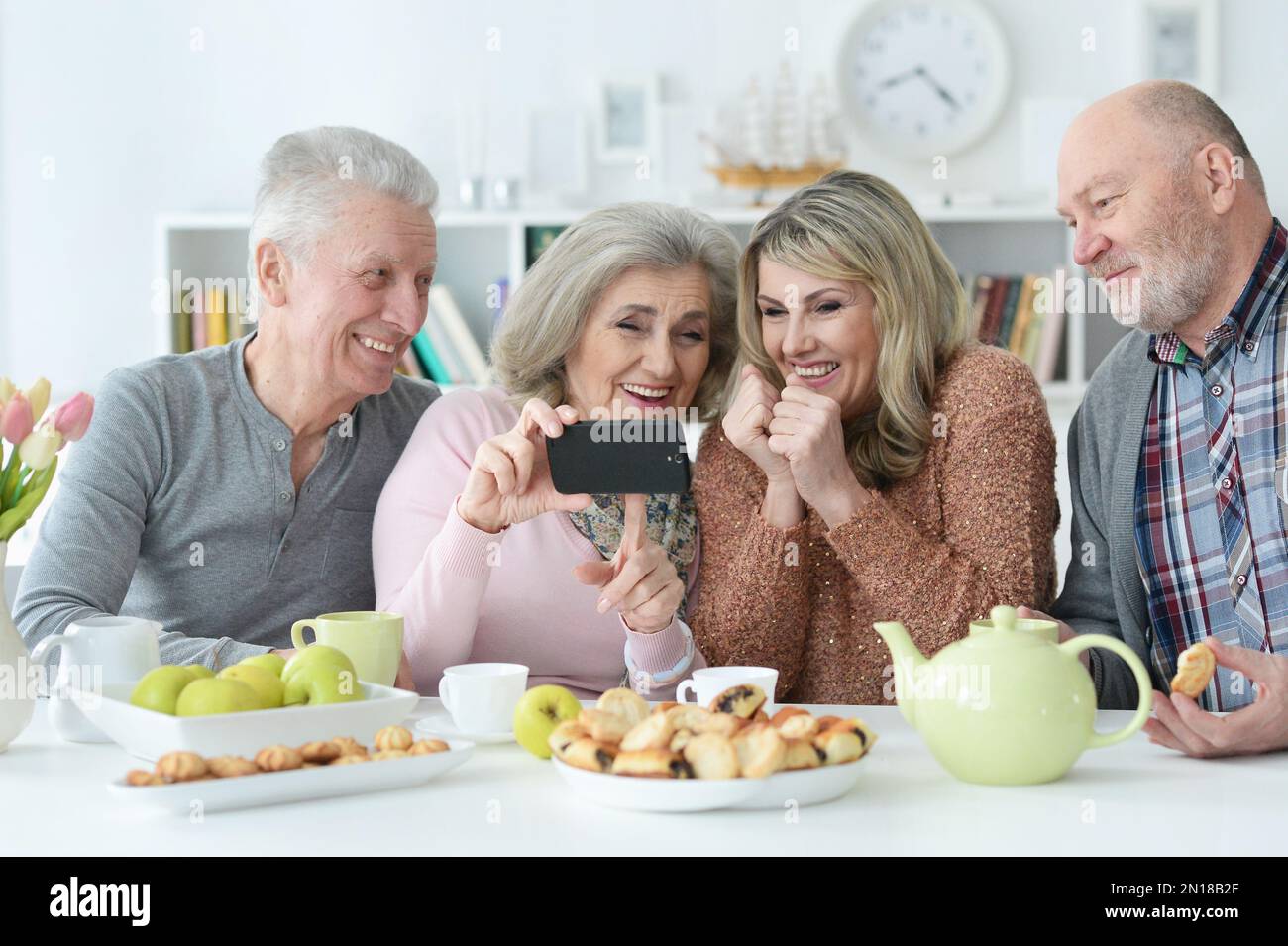 two Senior couples using smartphone during morning tea Stock Photo - Alamy