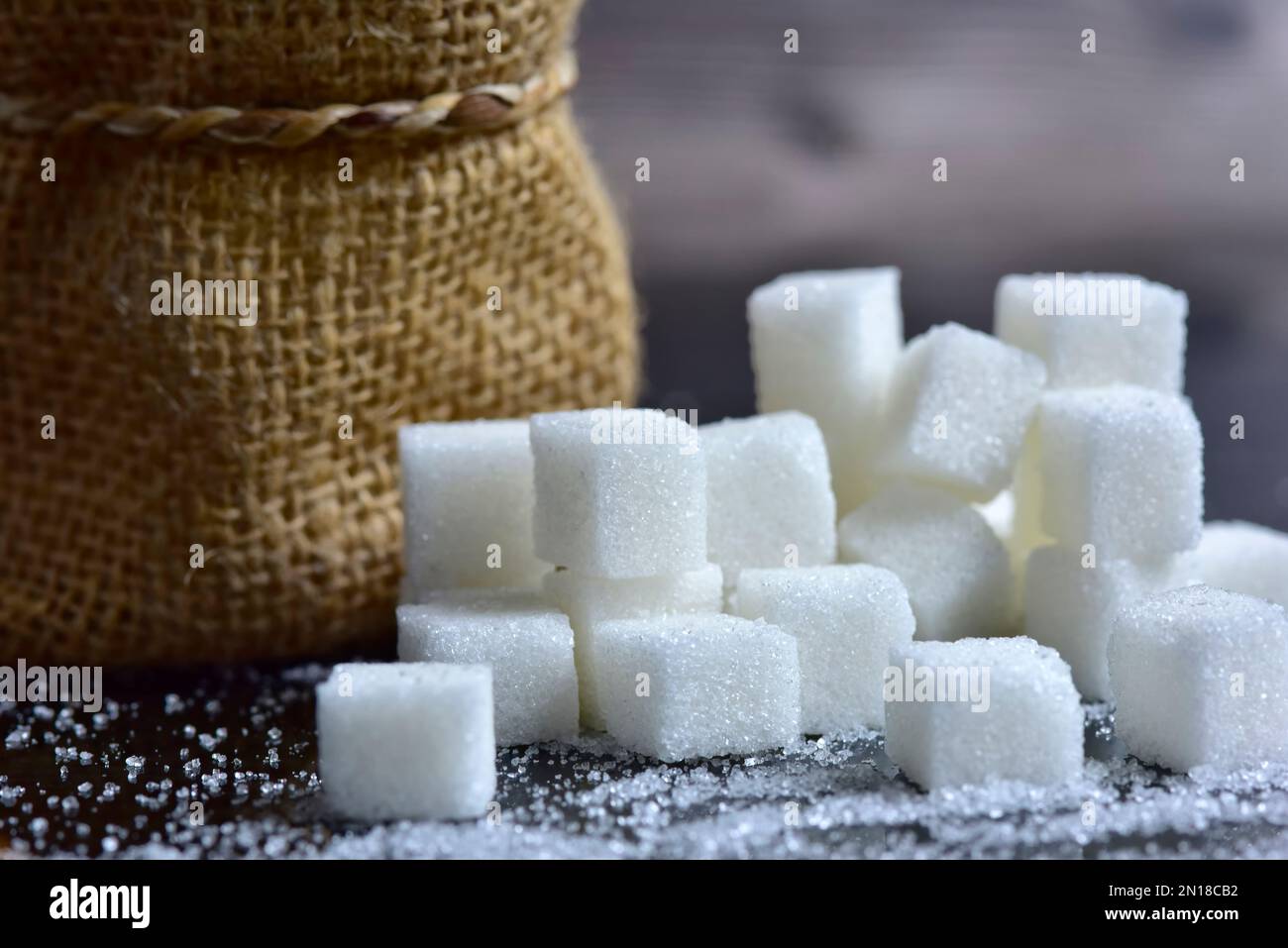 Closeup White sugar cubes and refined sugar in burlap sack bag on a ...