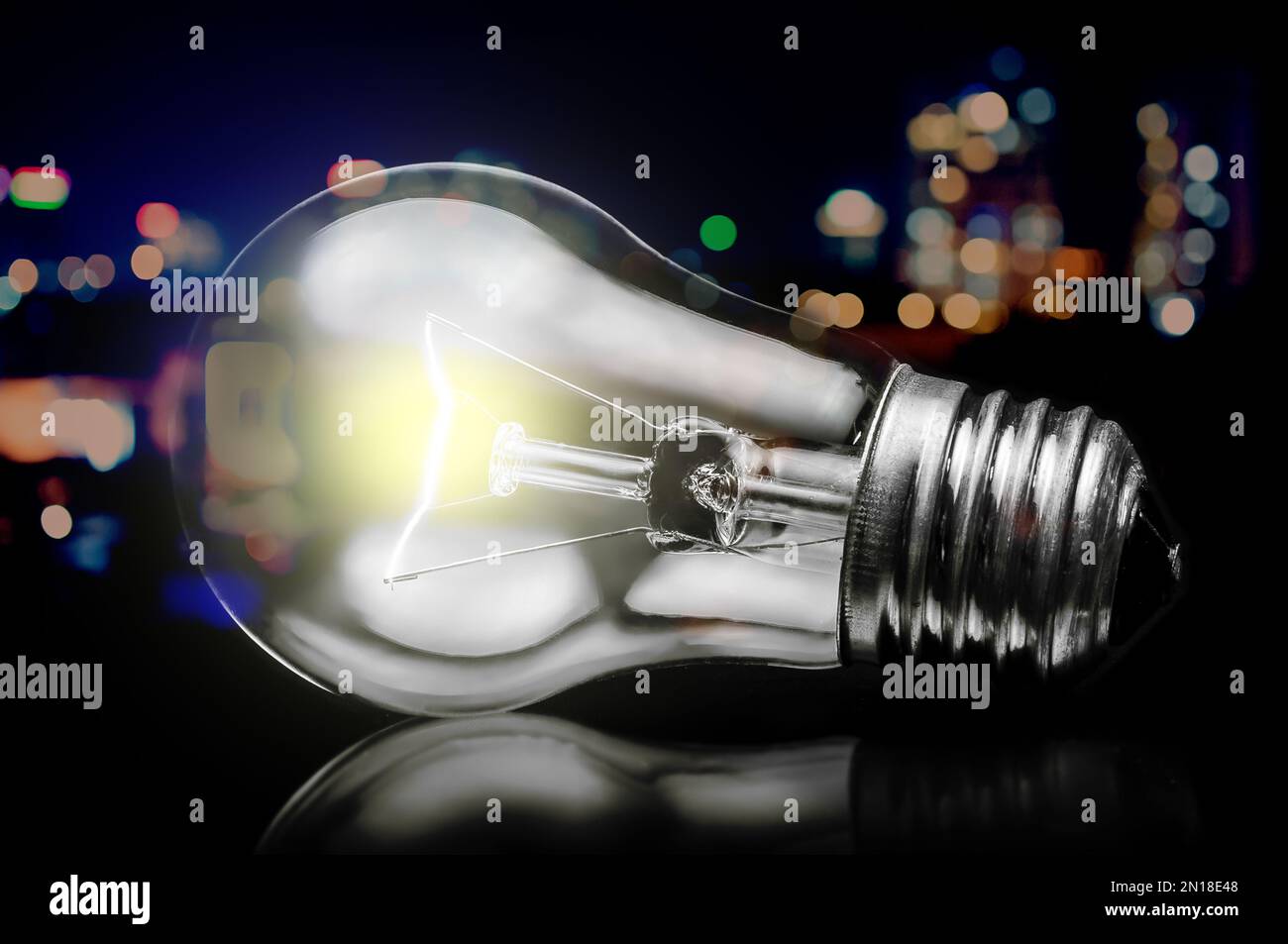 close up of tungsten light bulb with glow on dark background and night ...