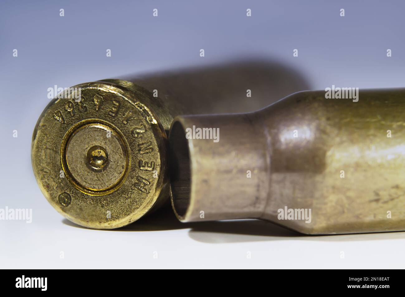 two machine gun cartridge cases on color gradient background close up ...