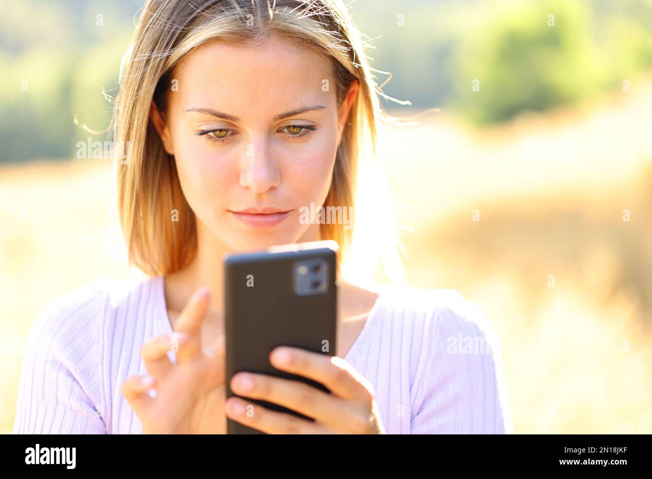 Front view portrait of a teen using cell phone in nature Stock Photo - Alamy